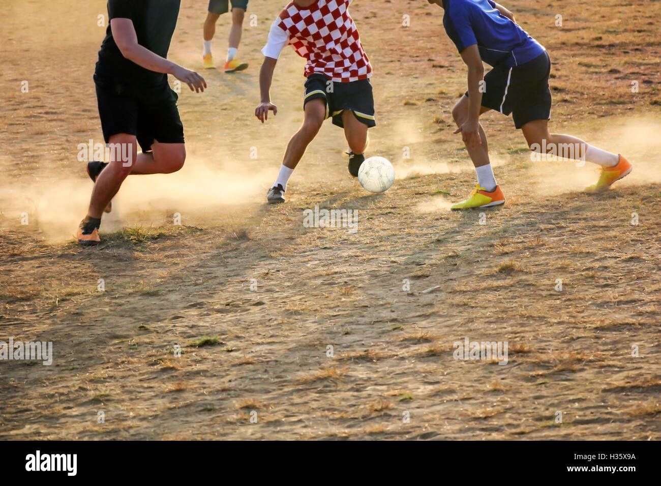 Young boys playing football game on the sunset Stock Photo - Alamy