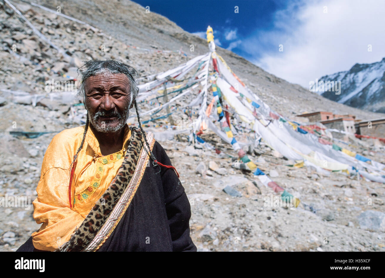Tibetan Buddhist monk with prayer flag covered flagpole and Dirapuk ...