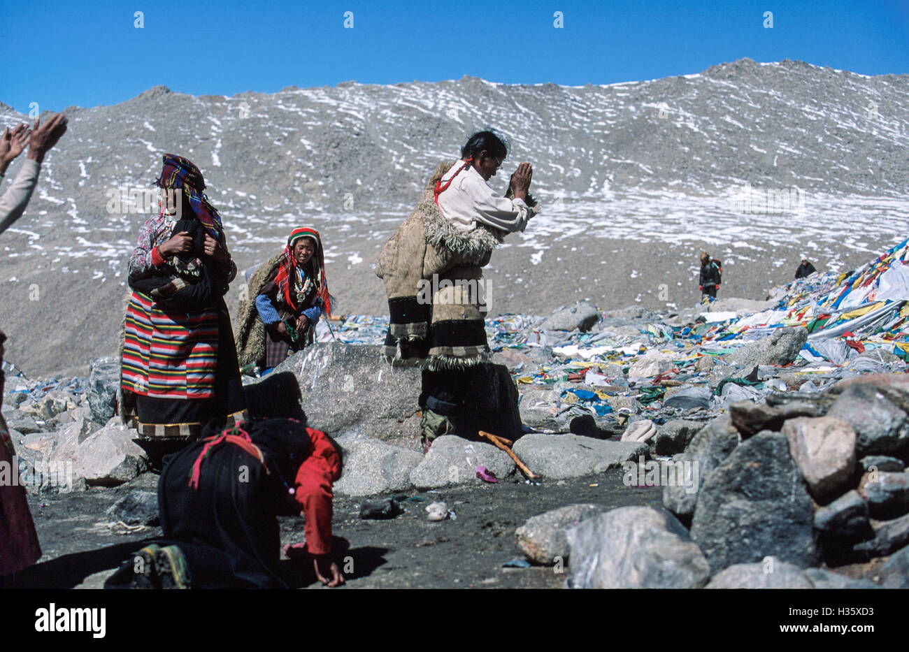 On reaching the high pass Tibetans pray at the prayer flag covered ...