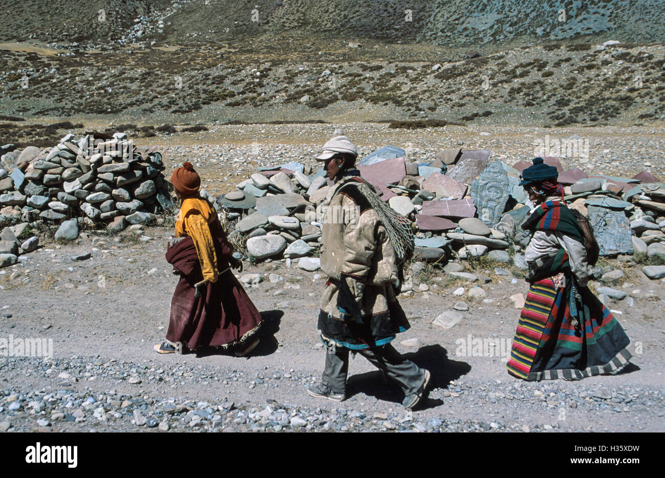 Tibetan pilgrims passing stone mani wall in the eastern valley known as ...