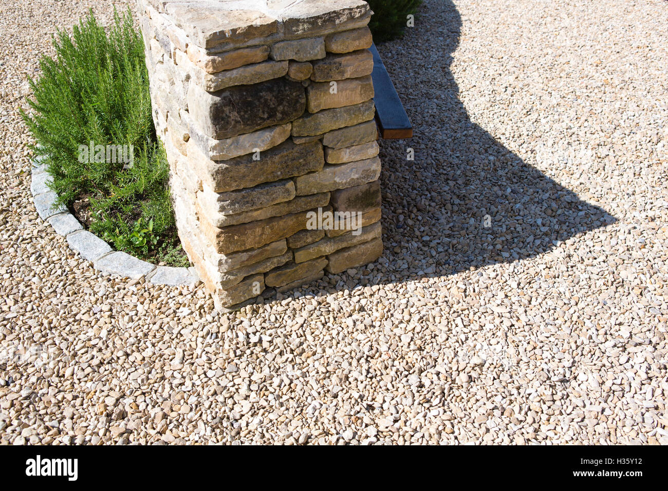 A gravel garden with low green bush and bench Stock Photo - Alamy