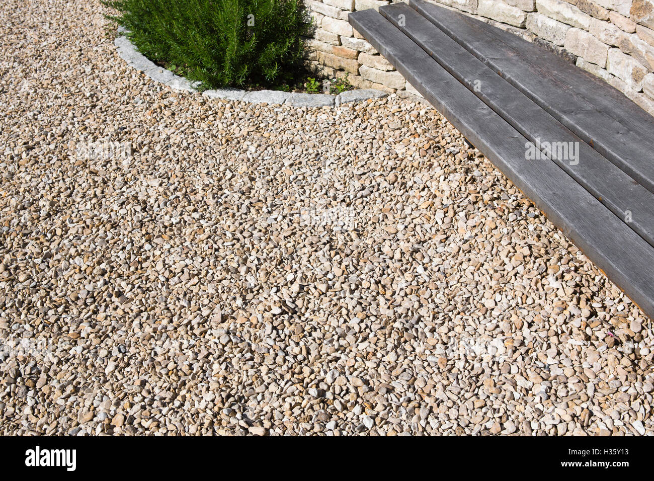 A gravel garden with low green bush and bench Stock Photo - Alamy