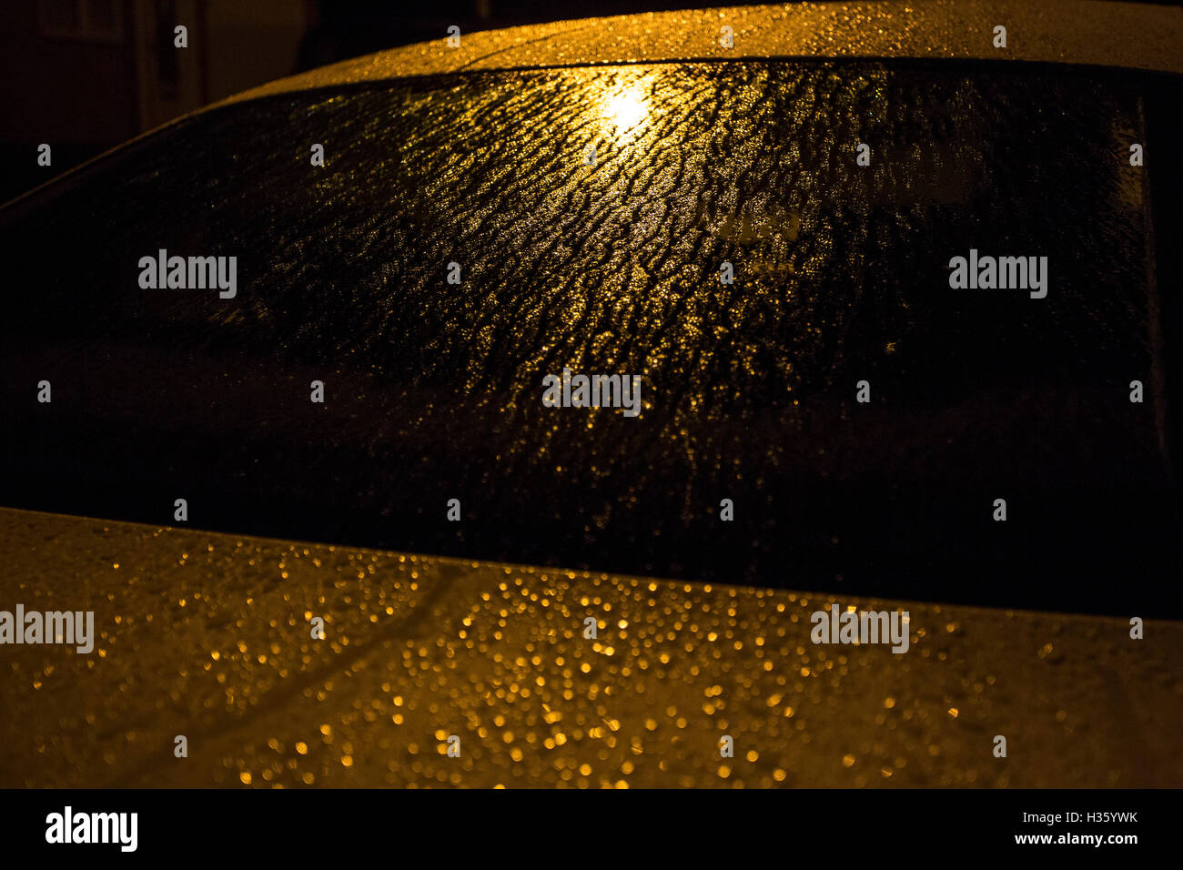 Back of a white car at night with drops of rain covering the window ...