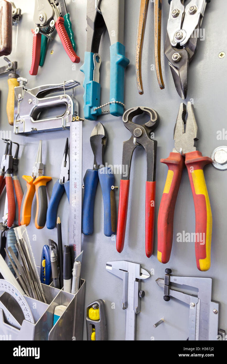 Set of work tools hanging on grey background Stock Photo - Alamy