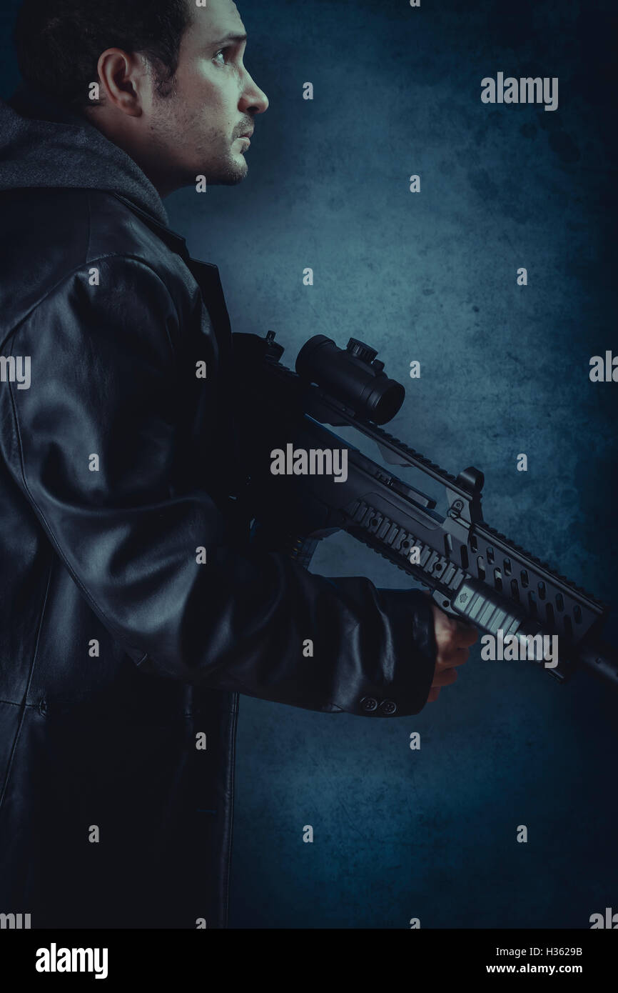 Man with long leather jacket and assault rifle Stock Photo - Alamy