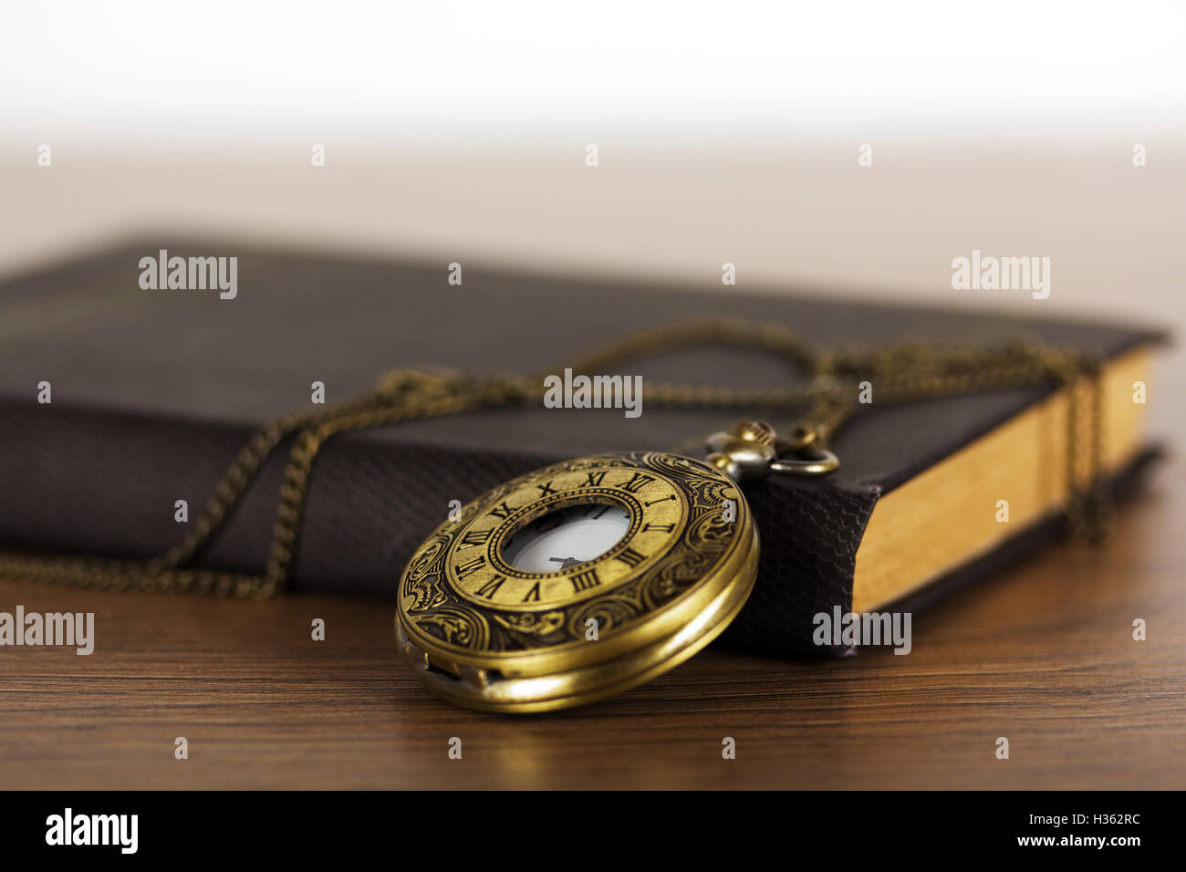 Pocket watch and book against a rustic wooden background Stock Photo ...