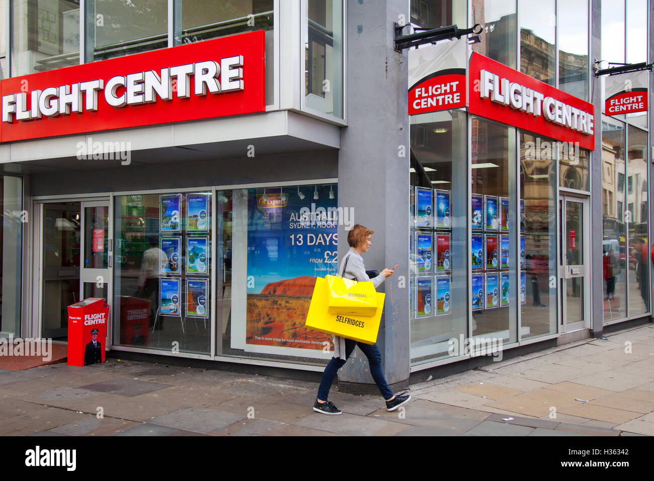 Blurred out of focus figures passing travel posters. People passing ...