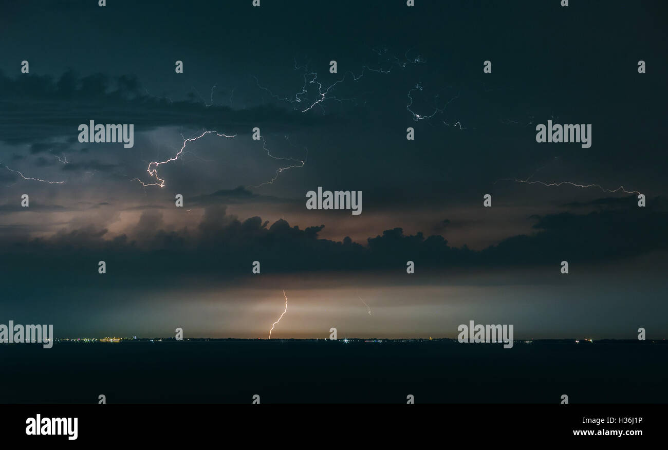 Massive cloud to ground lightning bolts hitting the horizon of city ...