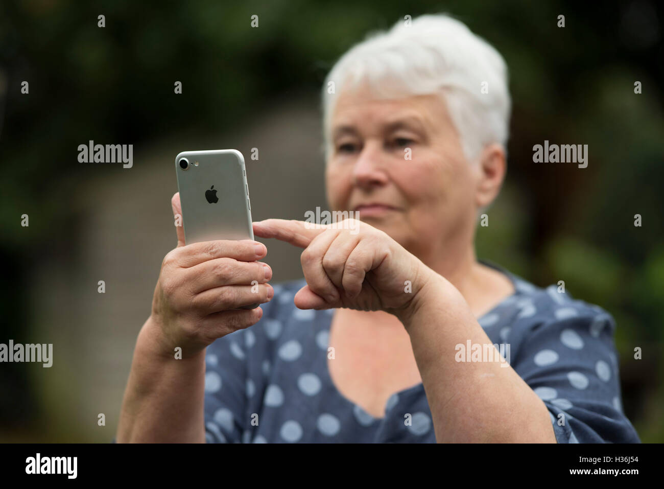 An elderly woman using an iPhone mobile phone Stock Photo - Alamy