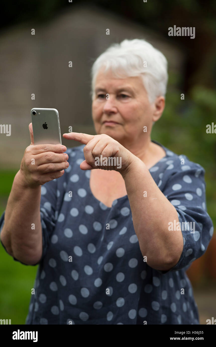 An elderly woman using an iPhone mobile phone Stock Photo - Alamy