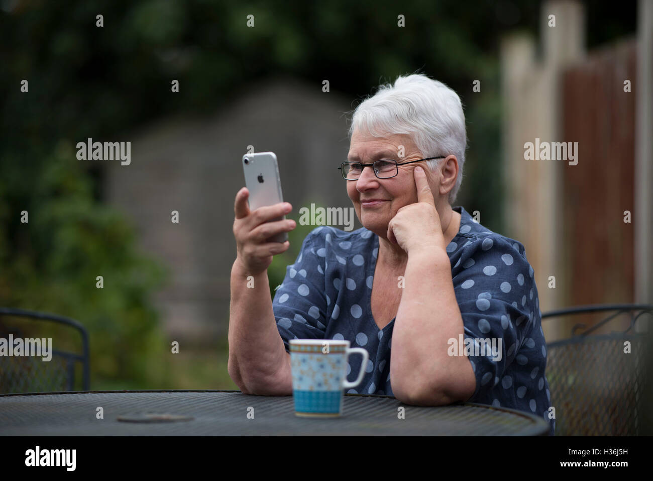 An elderly woman using an iPhone mobile phone Stock Photo - Alamy