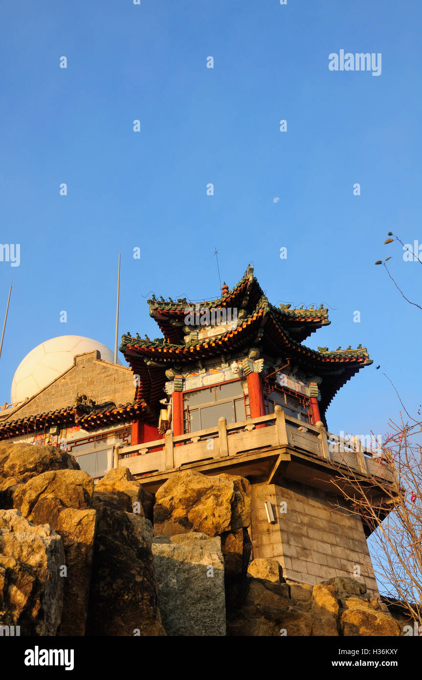 A Chinese style building under a waning moon in the morning sunlight on ...