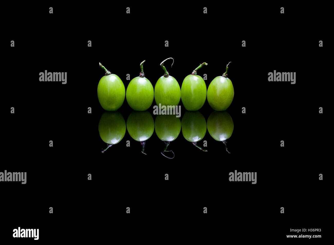 Five grapes on black reflective background Stock Photo - Alamy