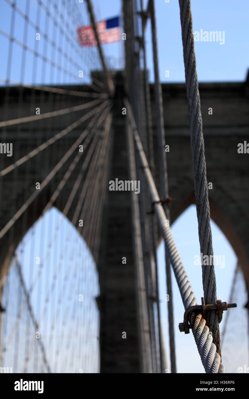Suspension cables on Brooklyn Bridge with American flag on bridge tower ...