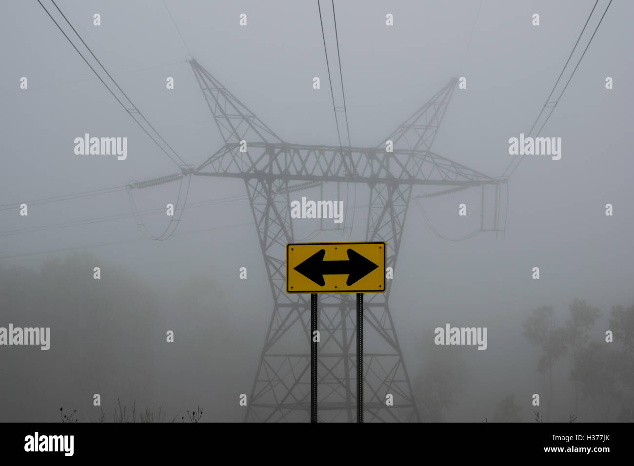 Yellow Directional Sign Near Powerlines in Fog Stock Photo - Alamy