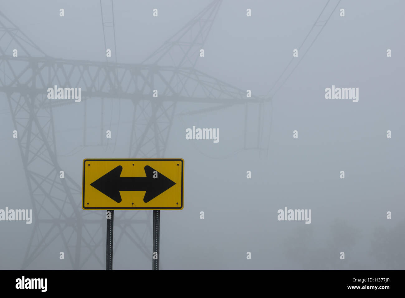 Yellow Directional Sign Near Powerlines in Fog Stock Photo - Alamy