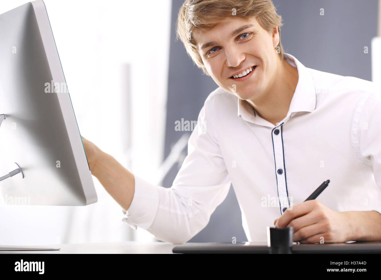 Working behind a desk, a handsome young employee Stock Photo - Alamy
