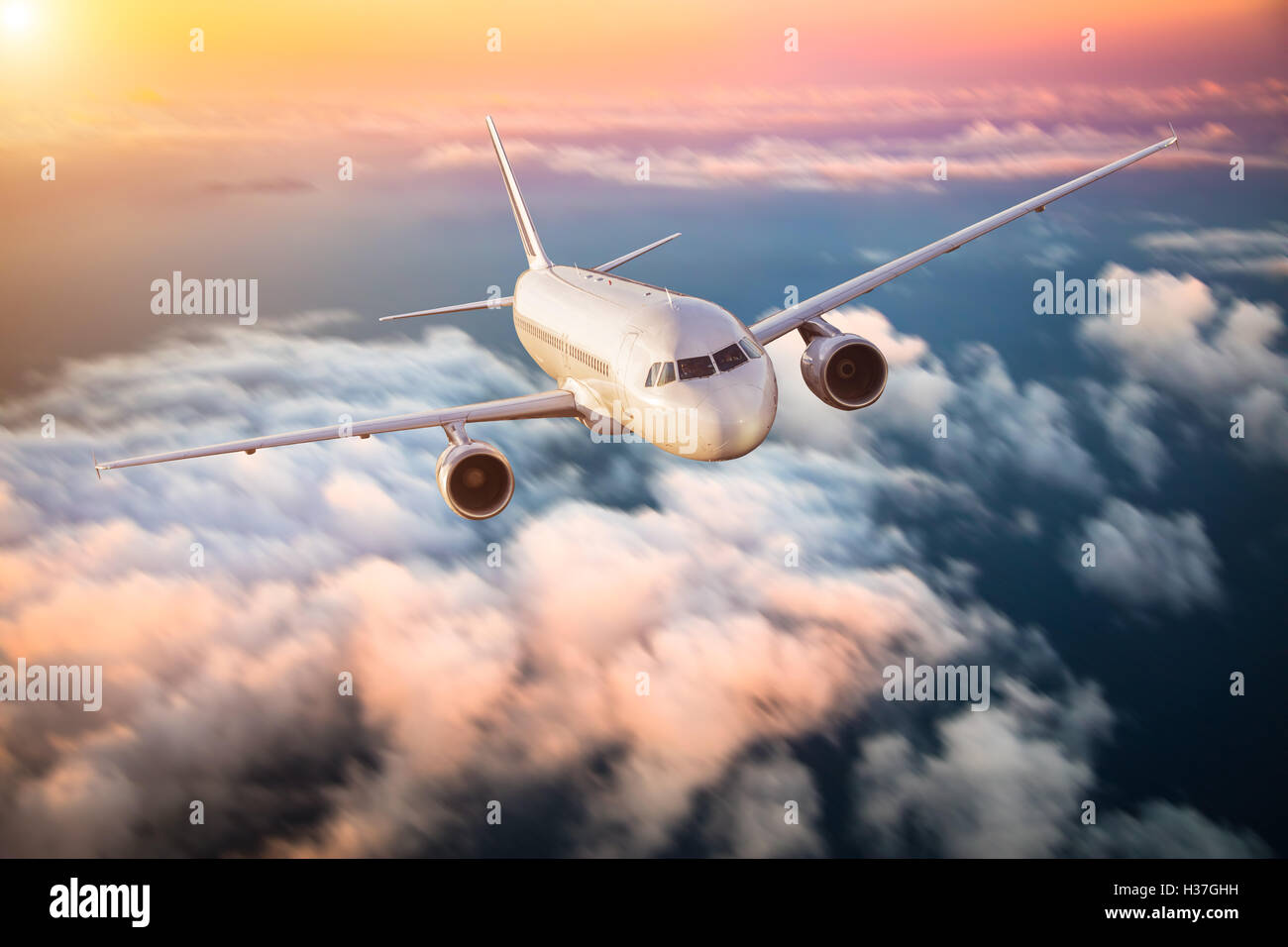 Commercial airplane flying above clouds in dramatic sunset light Stock ...
