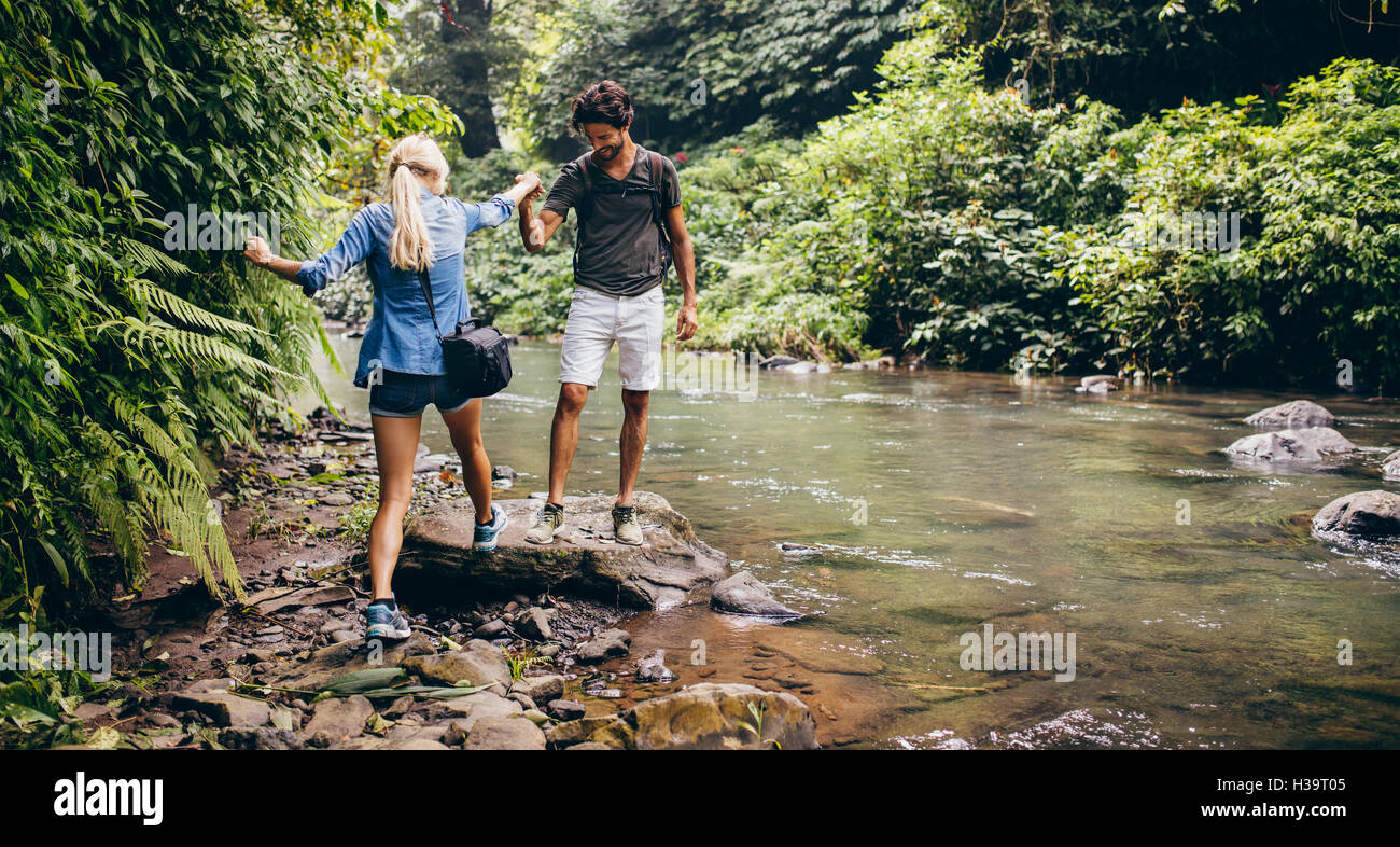 Two young hikers walking by mountain stream. Young couple walking on ...