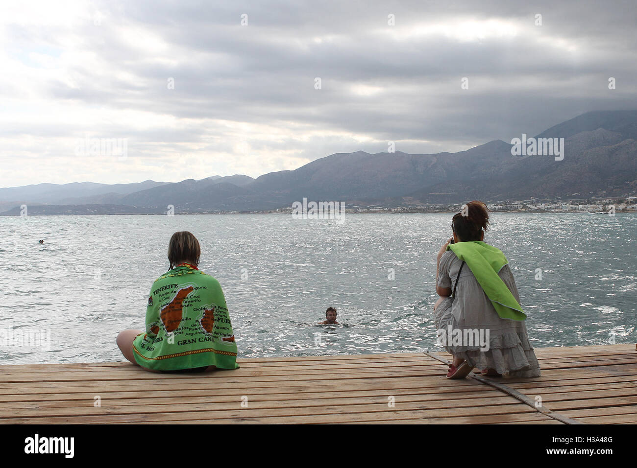 People look out on jetty towards the sea at Stalis Stalida Crete Greece ...