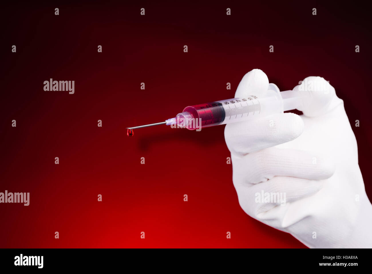 Hand pushing bloody syringe on red background Stock Photo - Alamy
