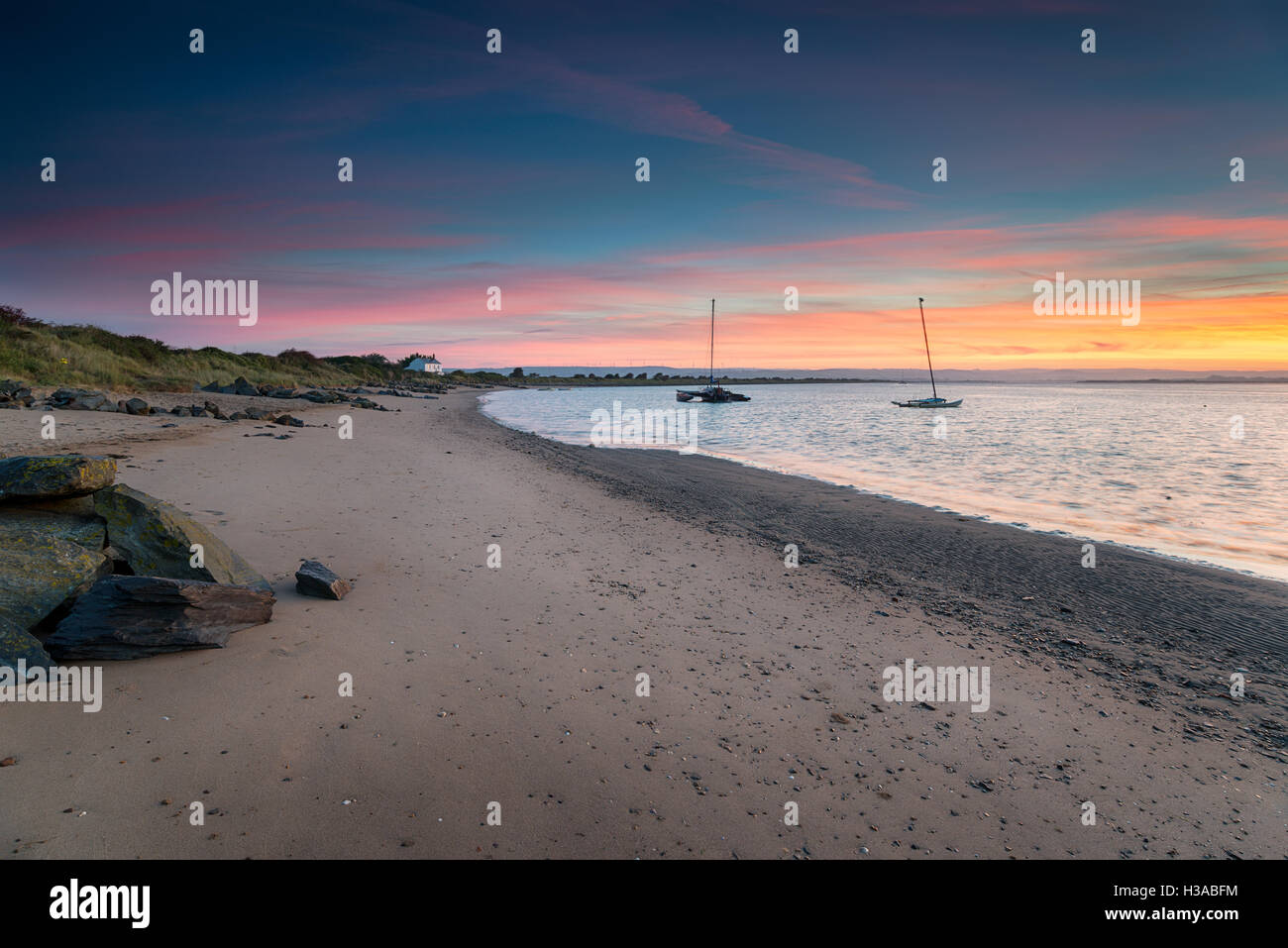 Stunning sunrise over a white cottage on the beach at Crow Point at ...
