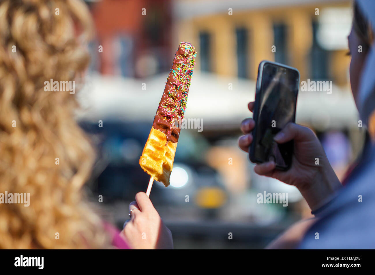 Delicious and colorful waffles in hands before eating Stock Photo - Alamy
