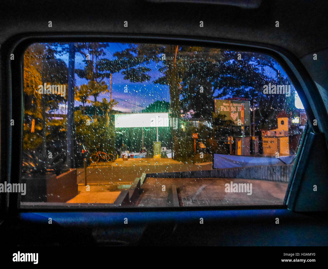 Rainy view through car window into sunset outside, blue red color sky ...