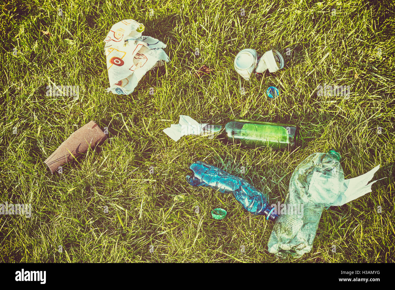 Retro sepia stylized lawn littered with garbage, environmental ...