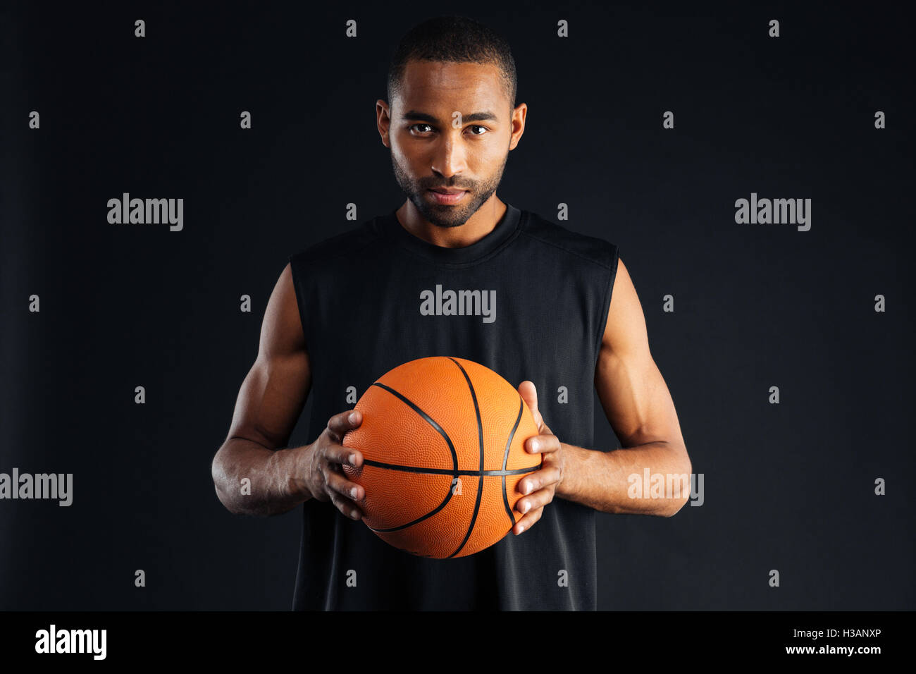 Portrait of a serious confident basketball player isolated on a black ...