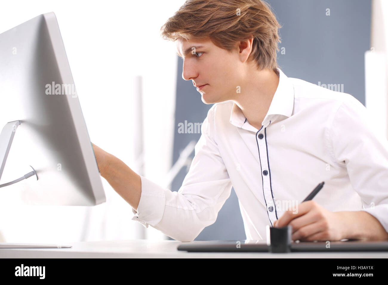 Working behind a desk, a handsome young employee Stock Photo - Alamy
