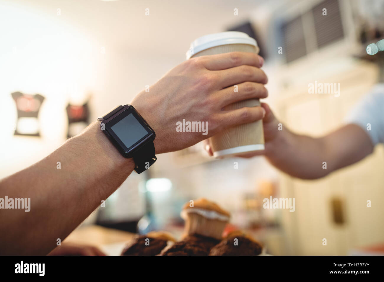 Close-up of customer with smart watch taking coffee from barista at ...
