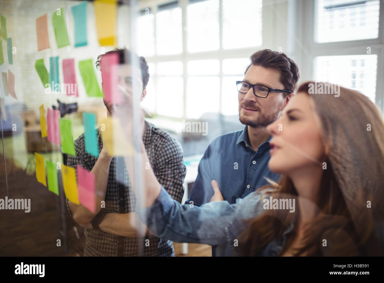 Business people writing on sticky notes seen through glass Stock Photo ...
