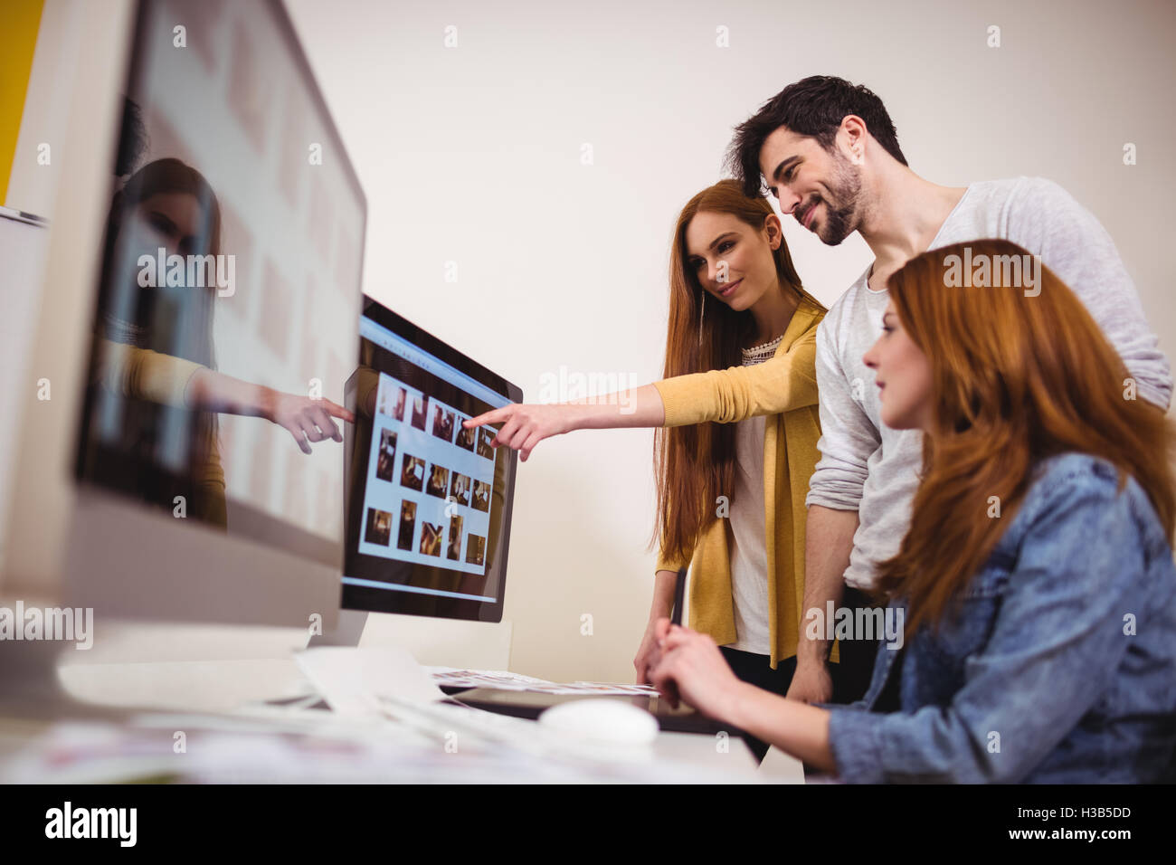 Businesswoman showing computer screen to coworkers Stock Photo - Alamy