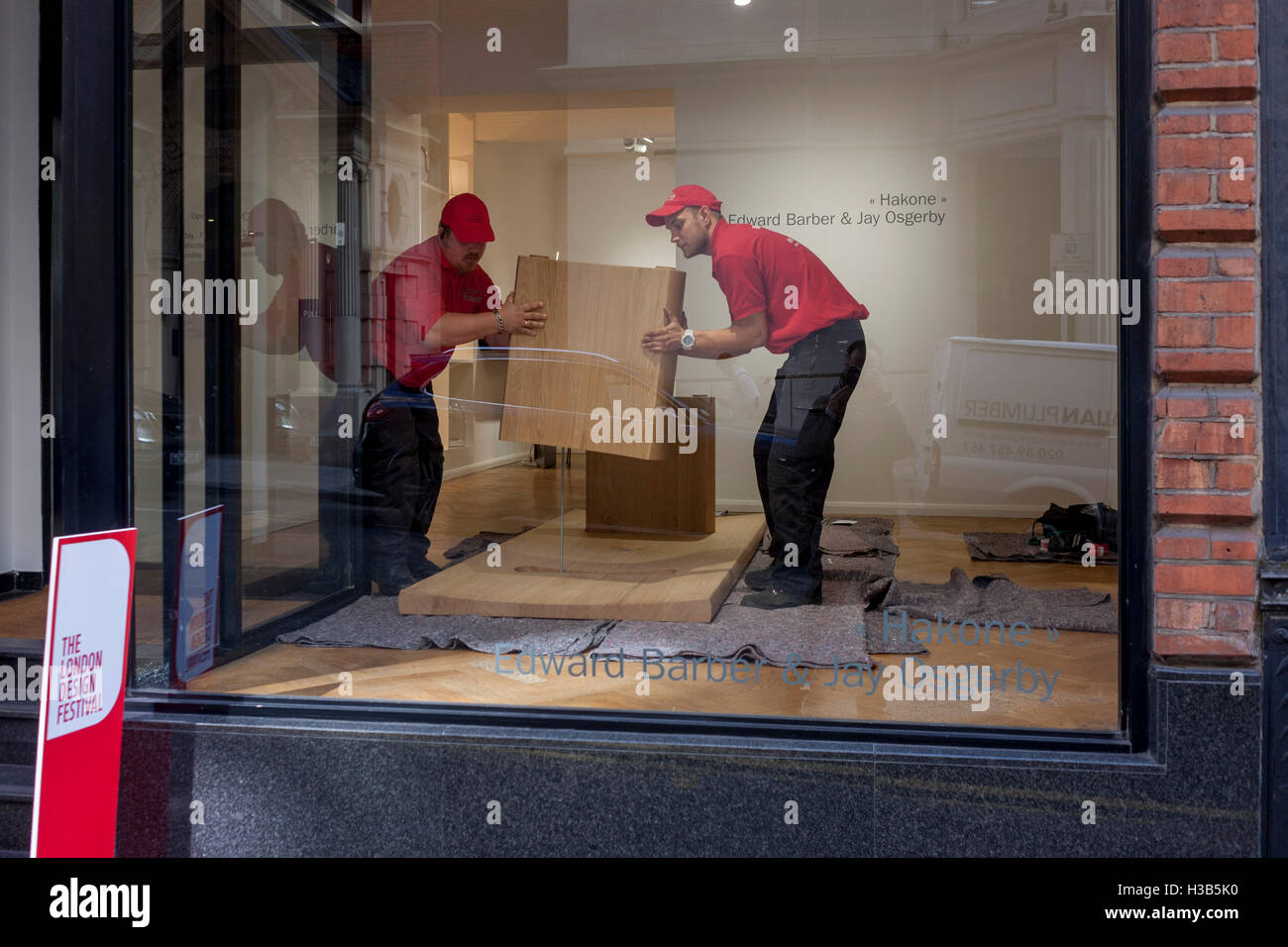 Two workmen carefully lift and place an exhibit, in the window of an ...