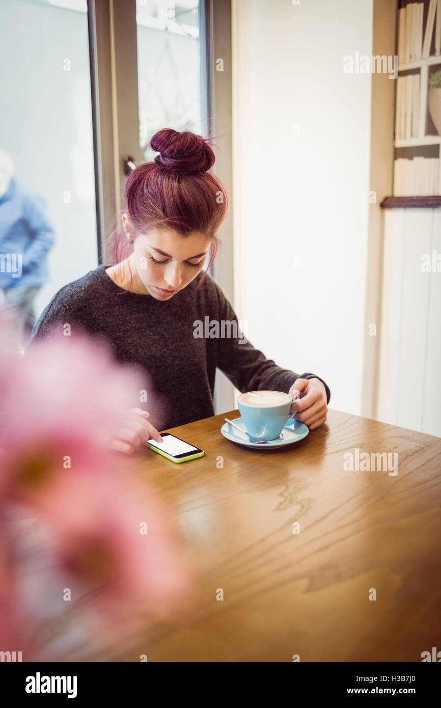 Hipster drinking a cup of coffee while using a smartphone Stock Photo ...