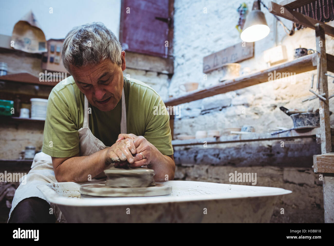 Concentrated craftsman making ceramic container in pottery workshop ...