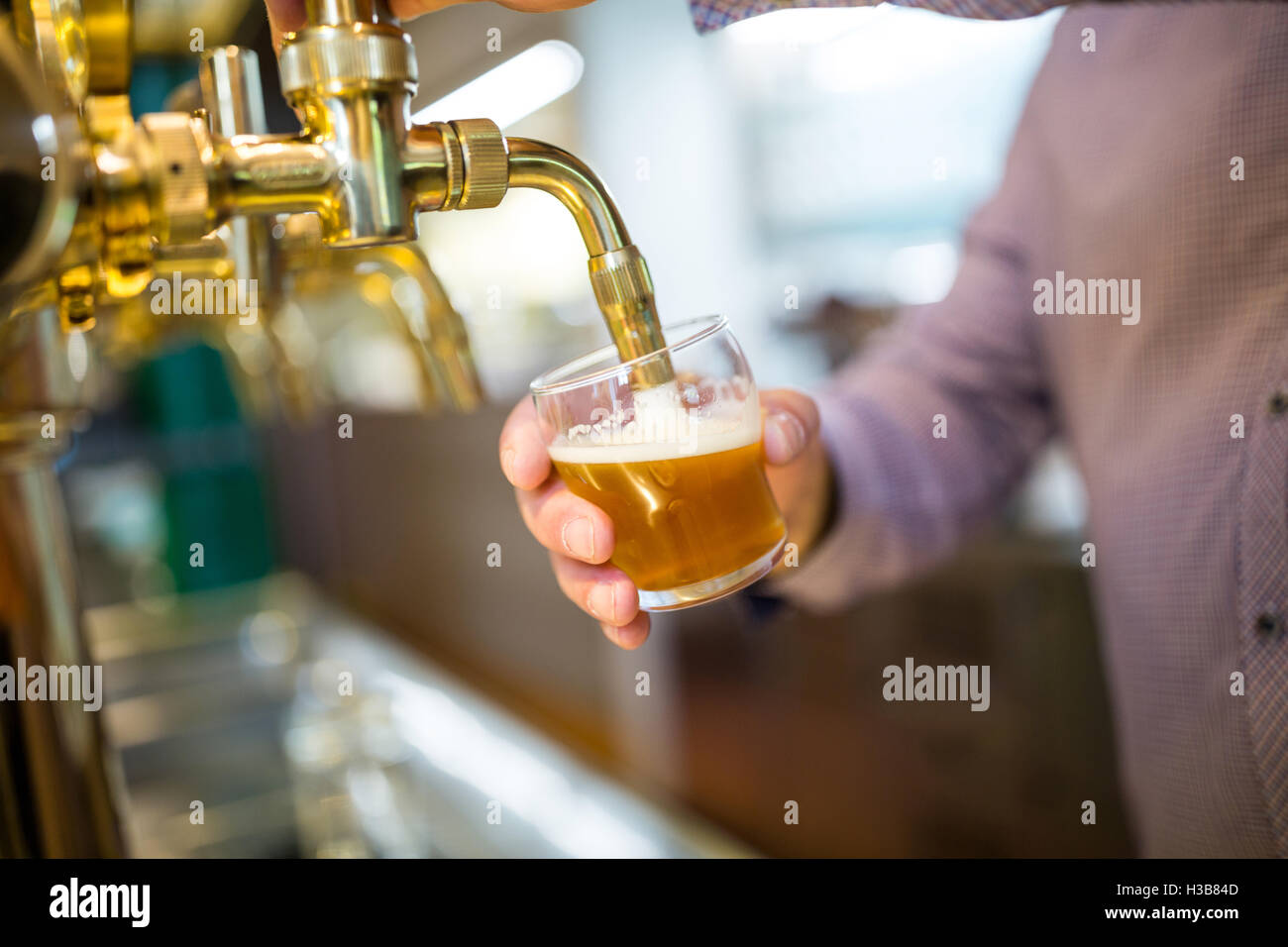Brewer filling beer in beer glass from beer pump Stock Photo - Alamy