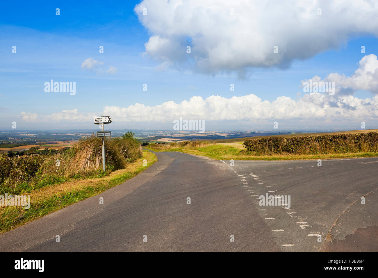 A hilltop road on the Yorkshire wolds with a sign post and views over ...