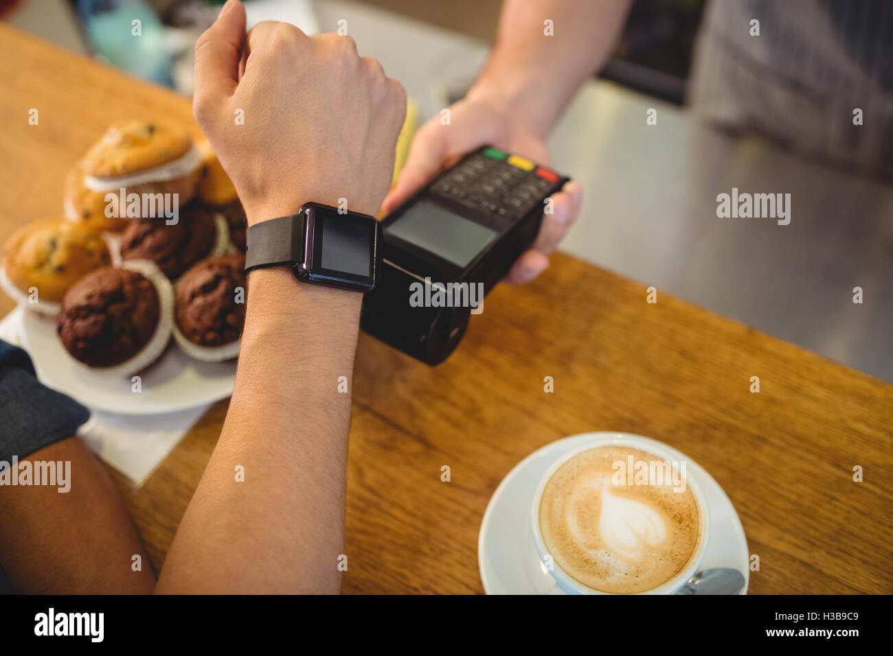 High angle view of customer wearing smart watch with barista holding ...
