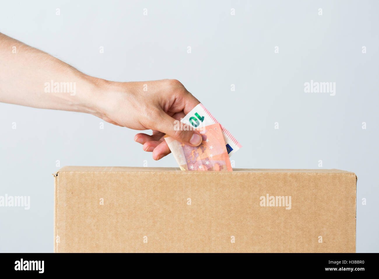 man putting euro money into donation box Stock Photo - Alamy