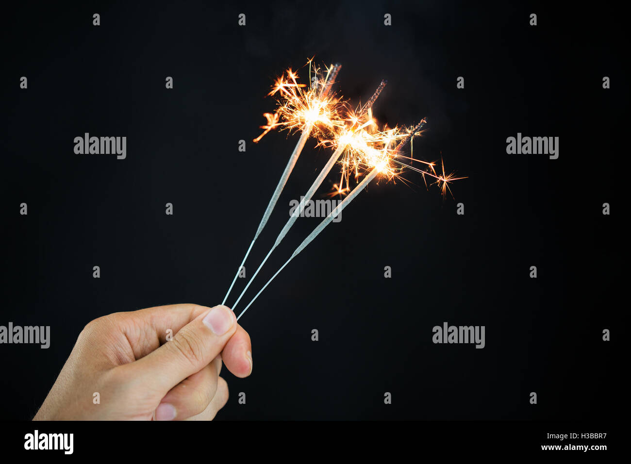 hand holding sparklers over black background Stock Photo - Alamy