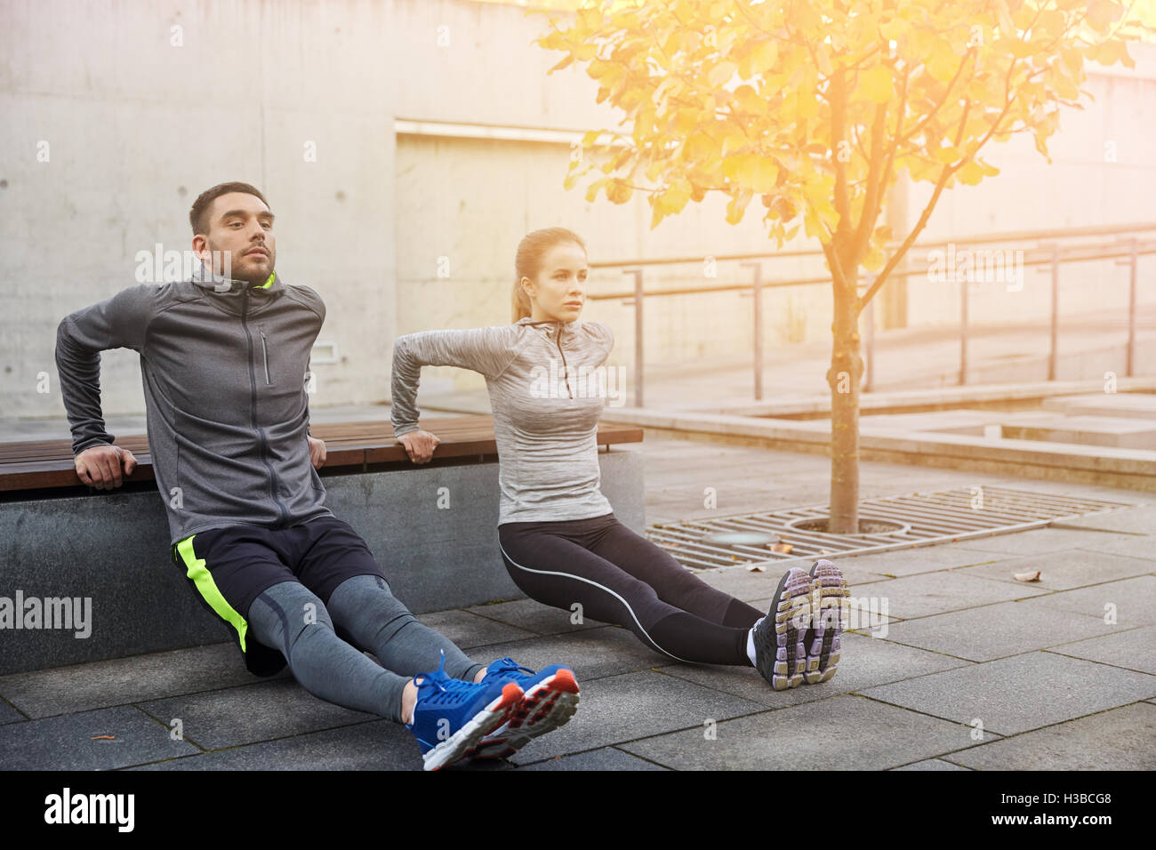 couple doing triceps dip on city street bench Stock Photo - Alamy