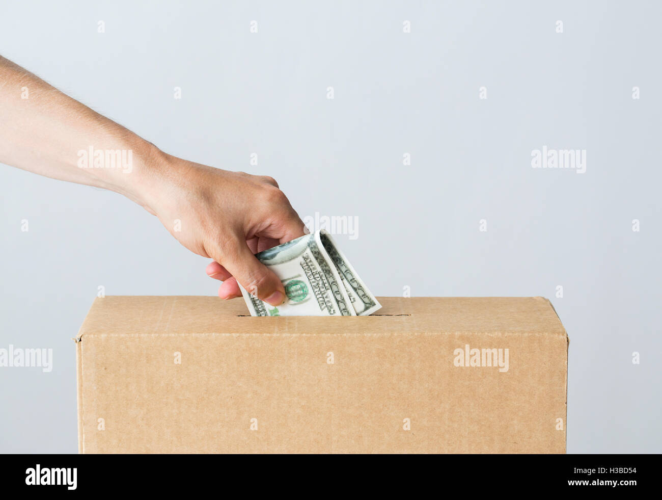 man putting dollar money into donation box Stock Photo - Alamy
