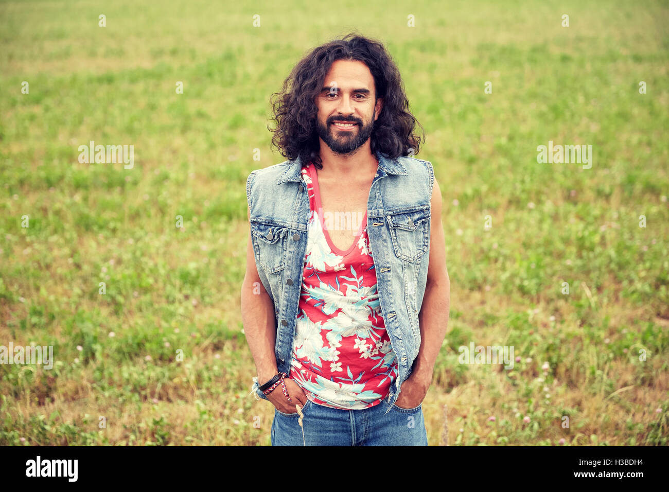 smiling young hippie man on green field Stock Photo - Alamy