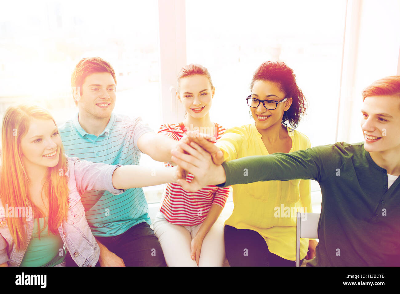 smiling students making high five gesture sitting Stock Photo - Alamy