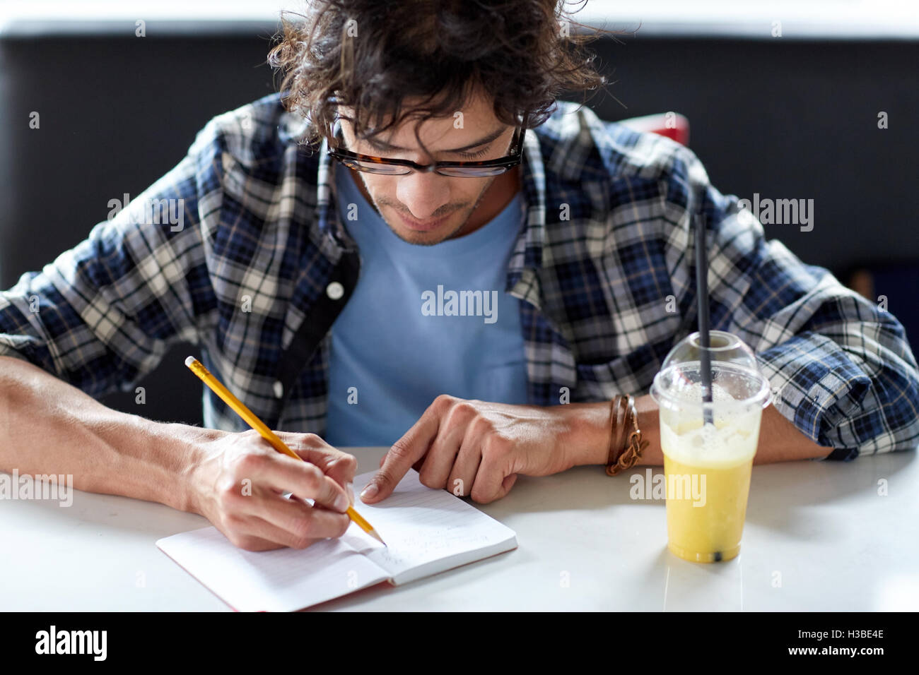 man with notebook and juice writing at cafe Stock Photo - Alamy