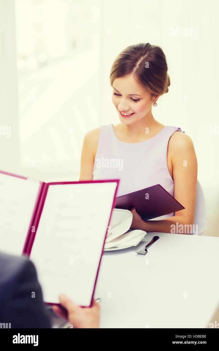 smiling young woman looking at menu at restaurant Stock Photo - Alamy