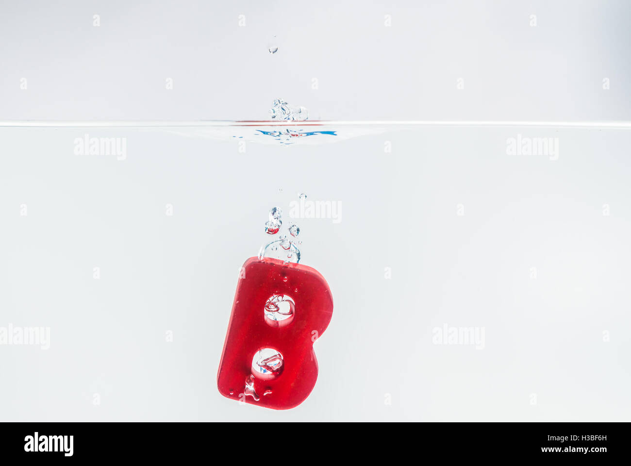 Red wooden alphabet B drop in the water with white background and ...