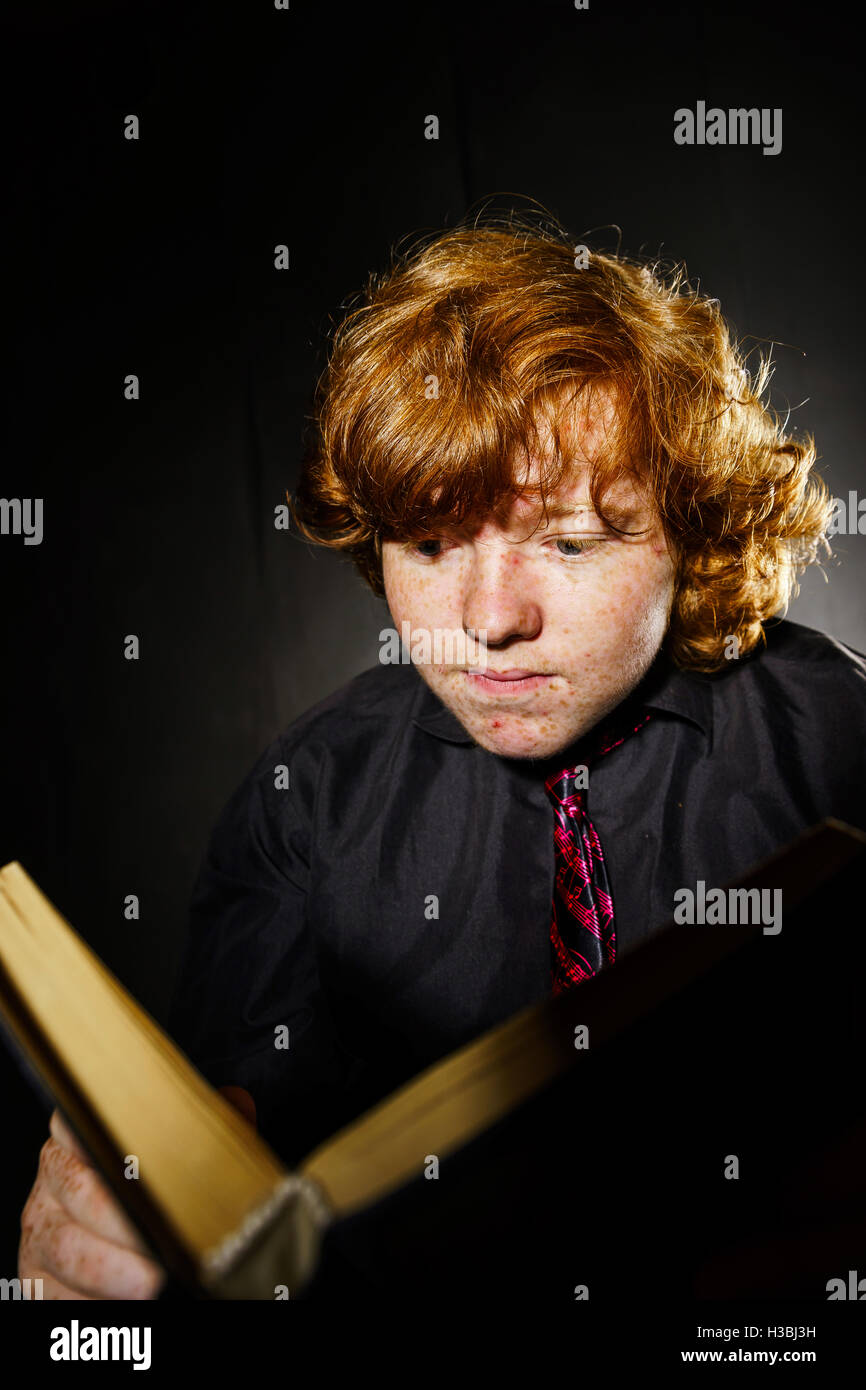 Freckled red-haired teenage boy reading book, education concept ...